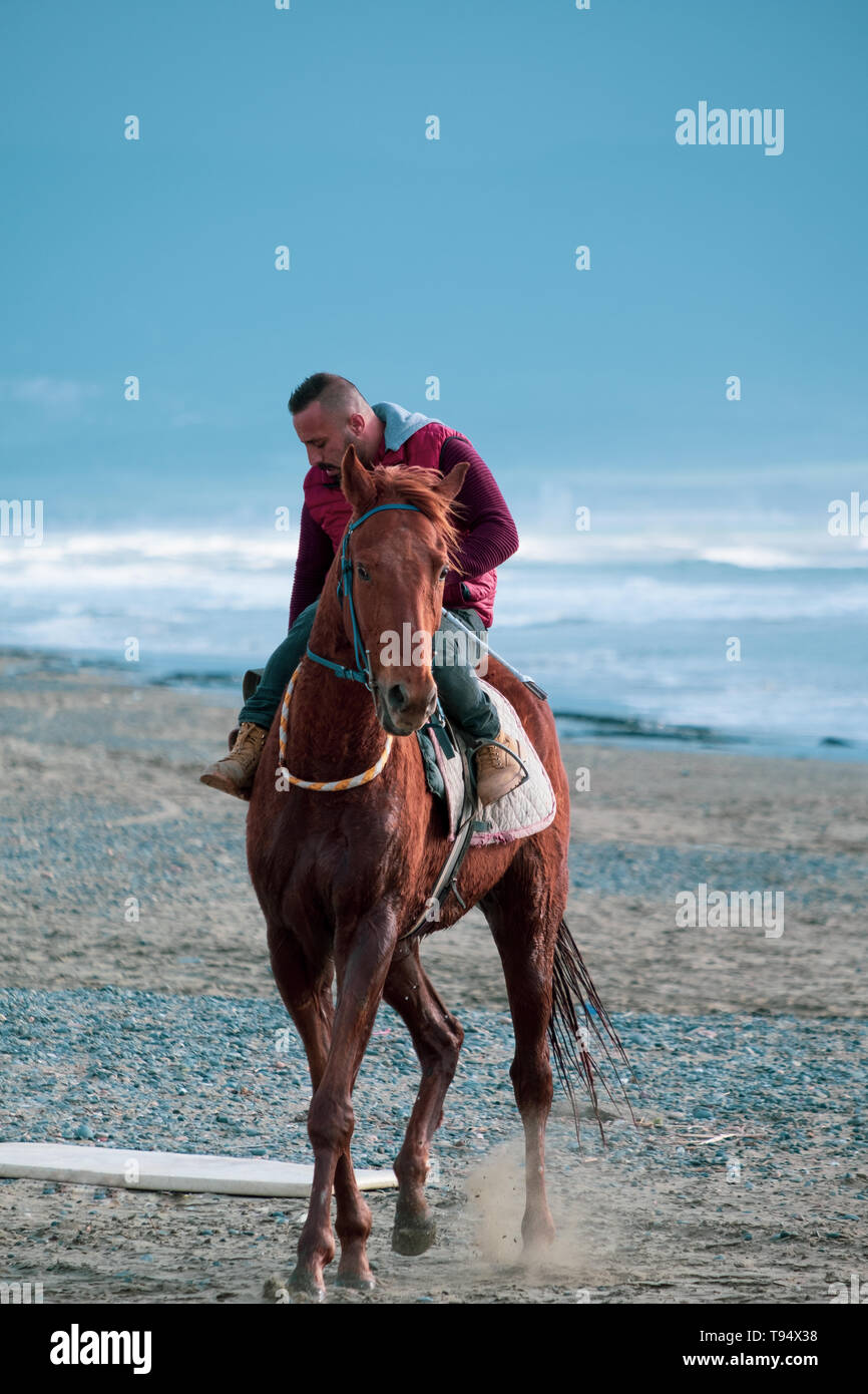 Ayia Eirini, Cyprus - 24 March, 2019: Man riding on a brown galloping ...