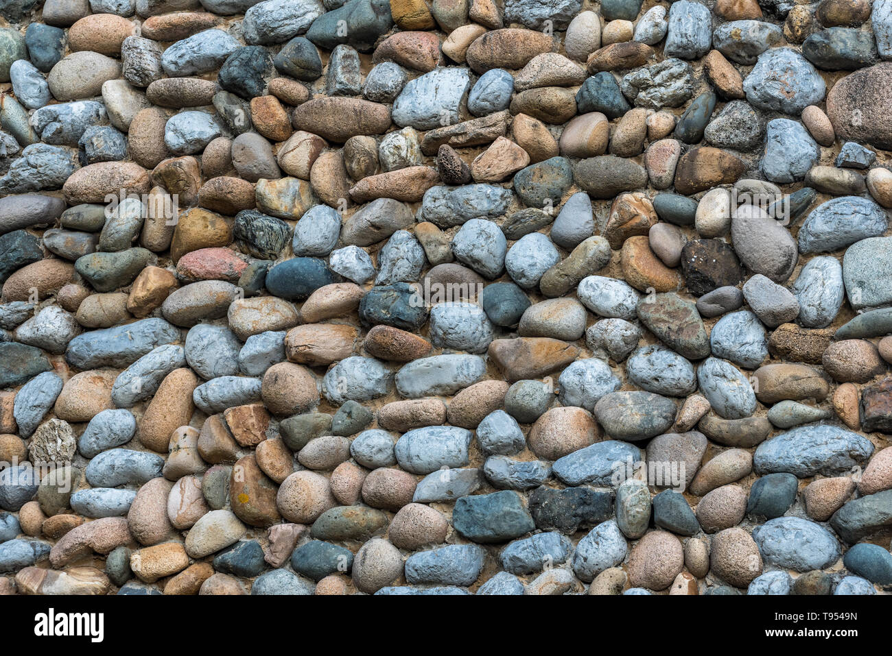 Different types of stones and pebbles of similar size arranged on flat ...