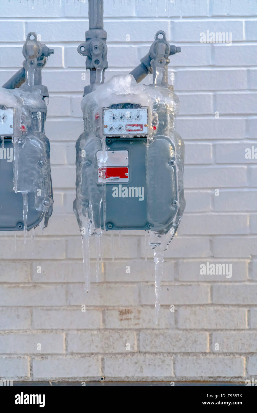 Close up view of a water meter outside a building with white brick wall ...