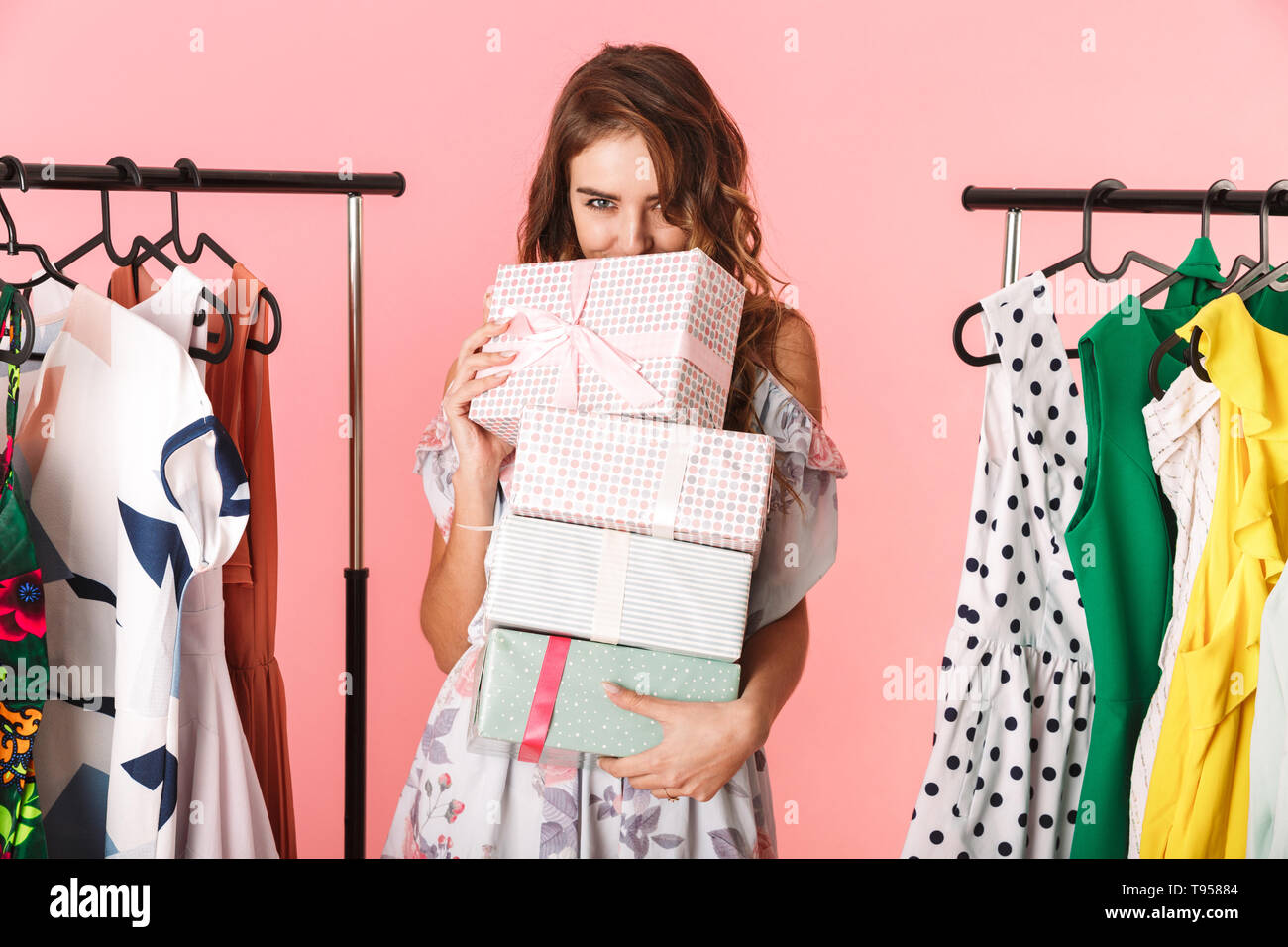Photo of modest woman wearing dress standing in store near clothes rack ...