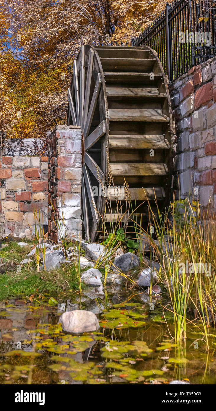 Clear Vertical Wooden water wheel and flume at a reflective pond with ...