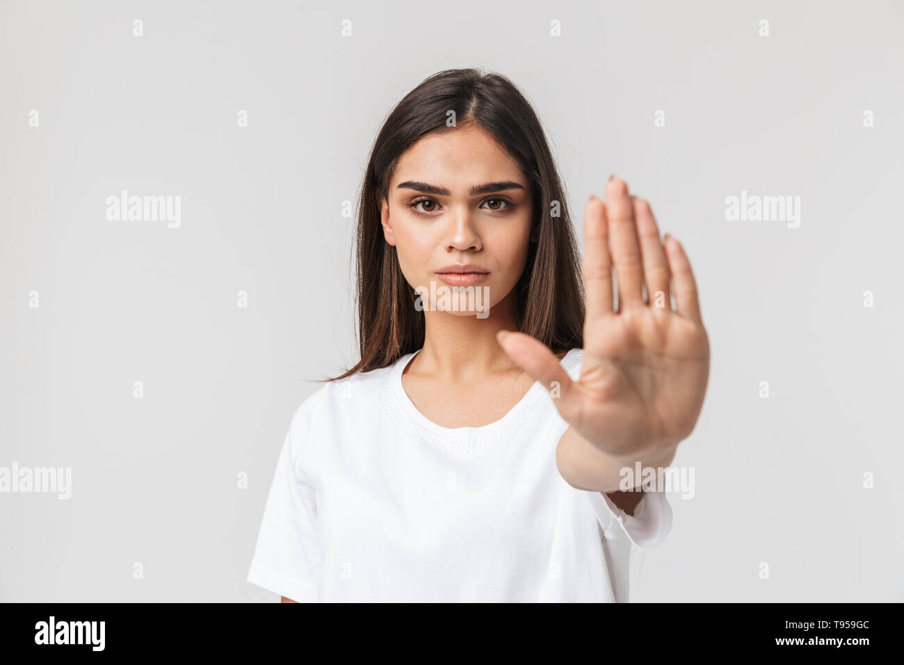 Serious young girl standing isolated over white background, showing ...