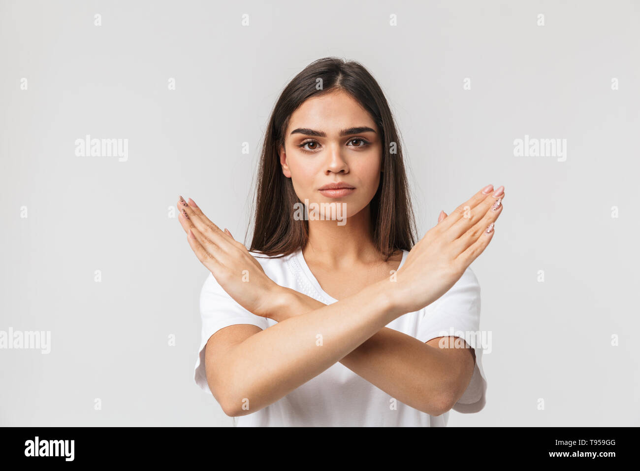 Serious young girl standing isolated over white background, showing ...