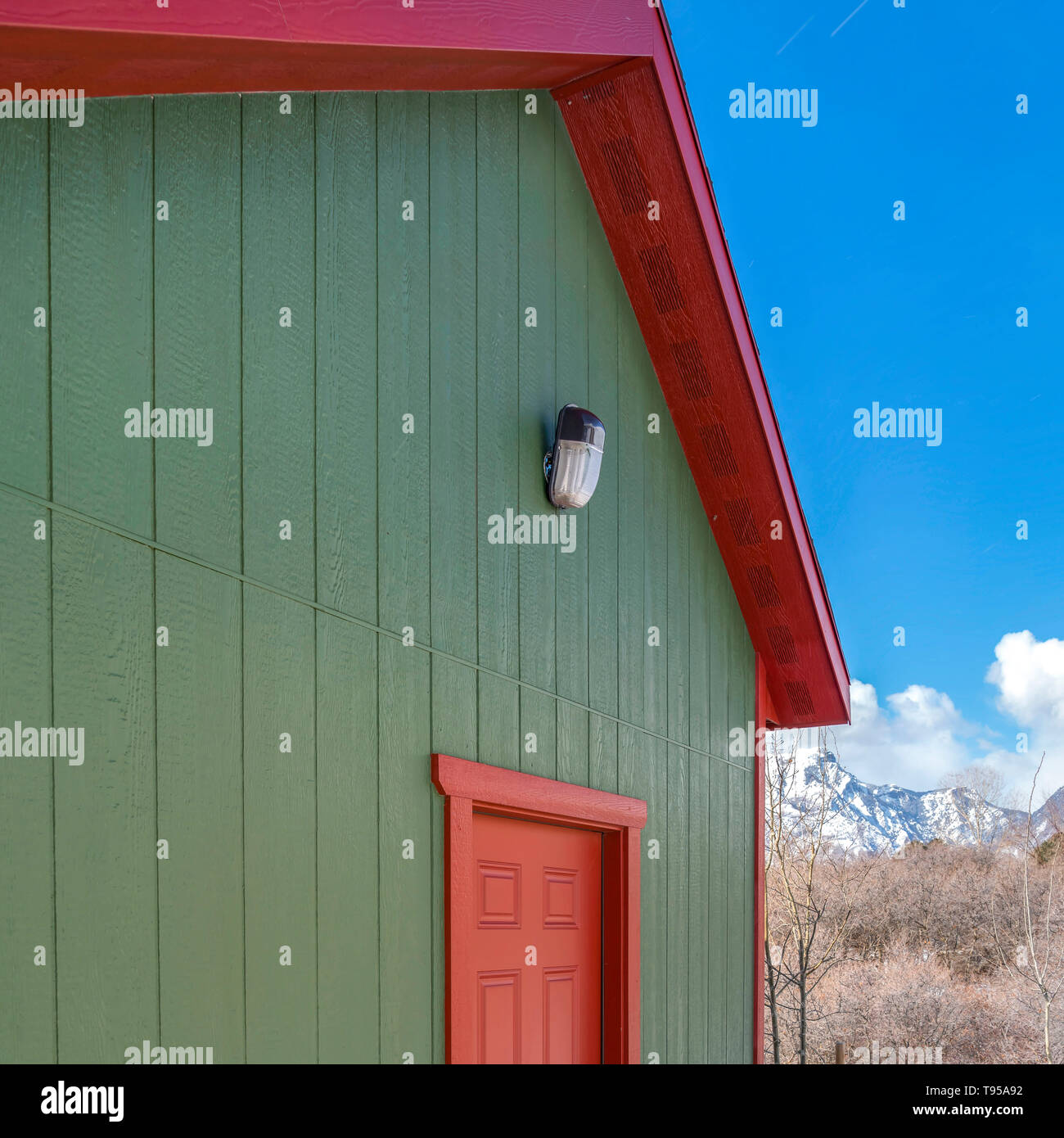 Square Storage shed against trees and snow capped mountain under cloudy ...
