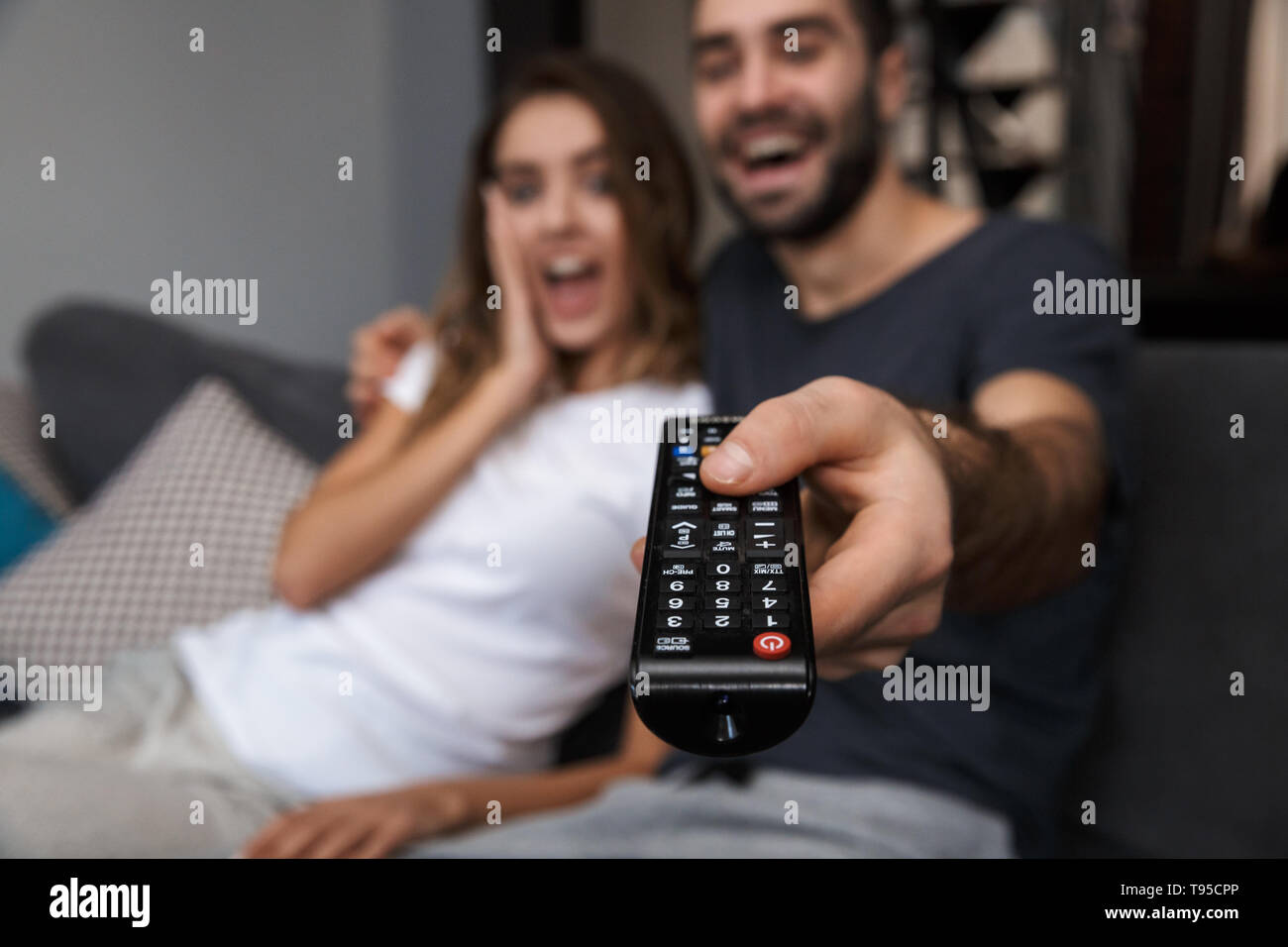 Cheerful young couple relaxing on couch at home, watching tv Stock ...