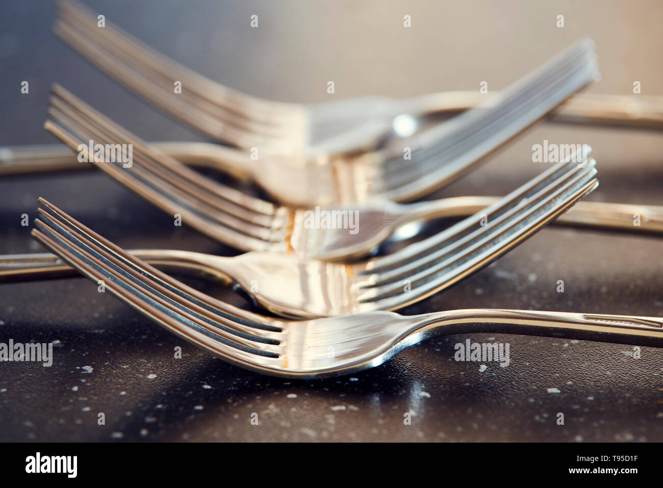 Crossed five steel forks on black table. Macro photography for dishware ...