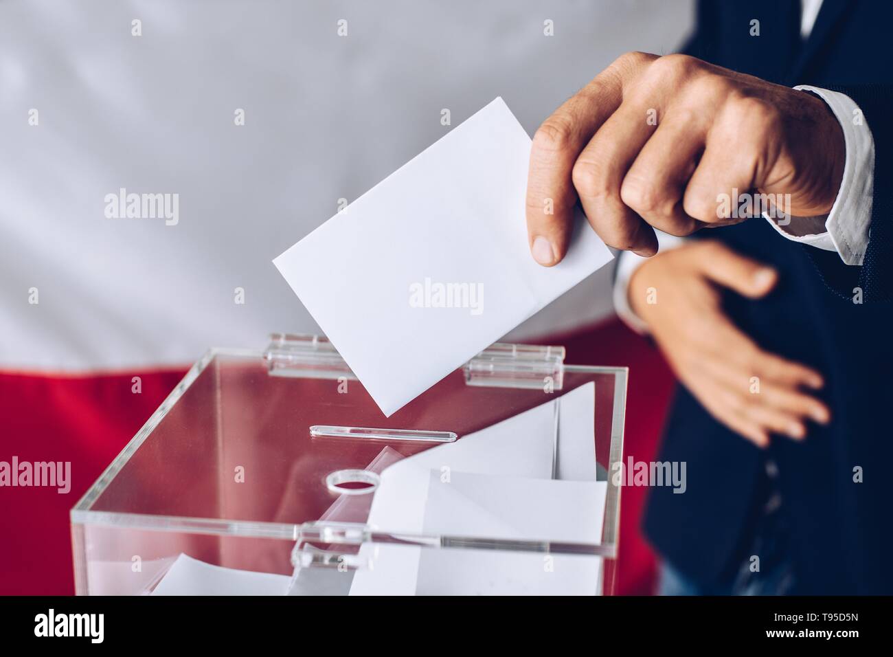 Man throwing his vote into the ballot box. Polish flag in the ...