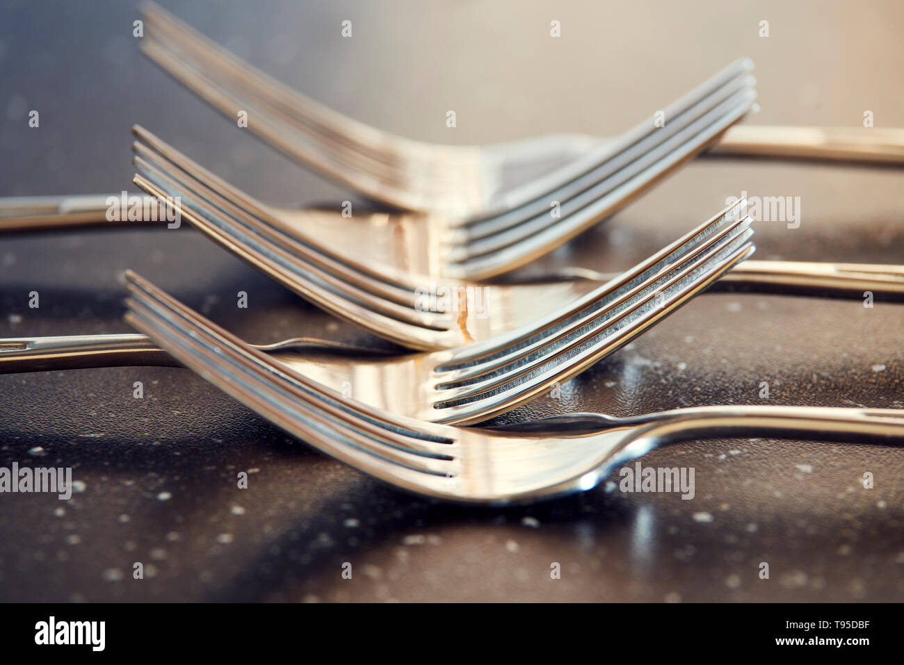 Crossed five steel forks on black table. Macro photography for dishware ...