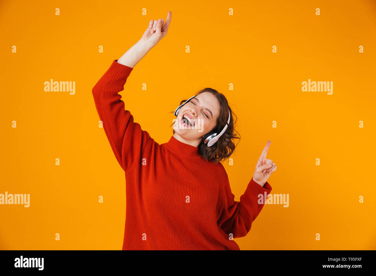 Portrait of beautiful woman 20s wearing wireless headphones dancing and ...