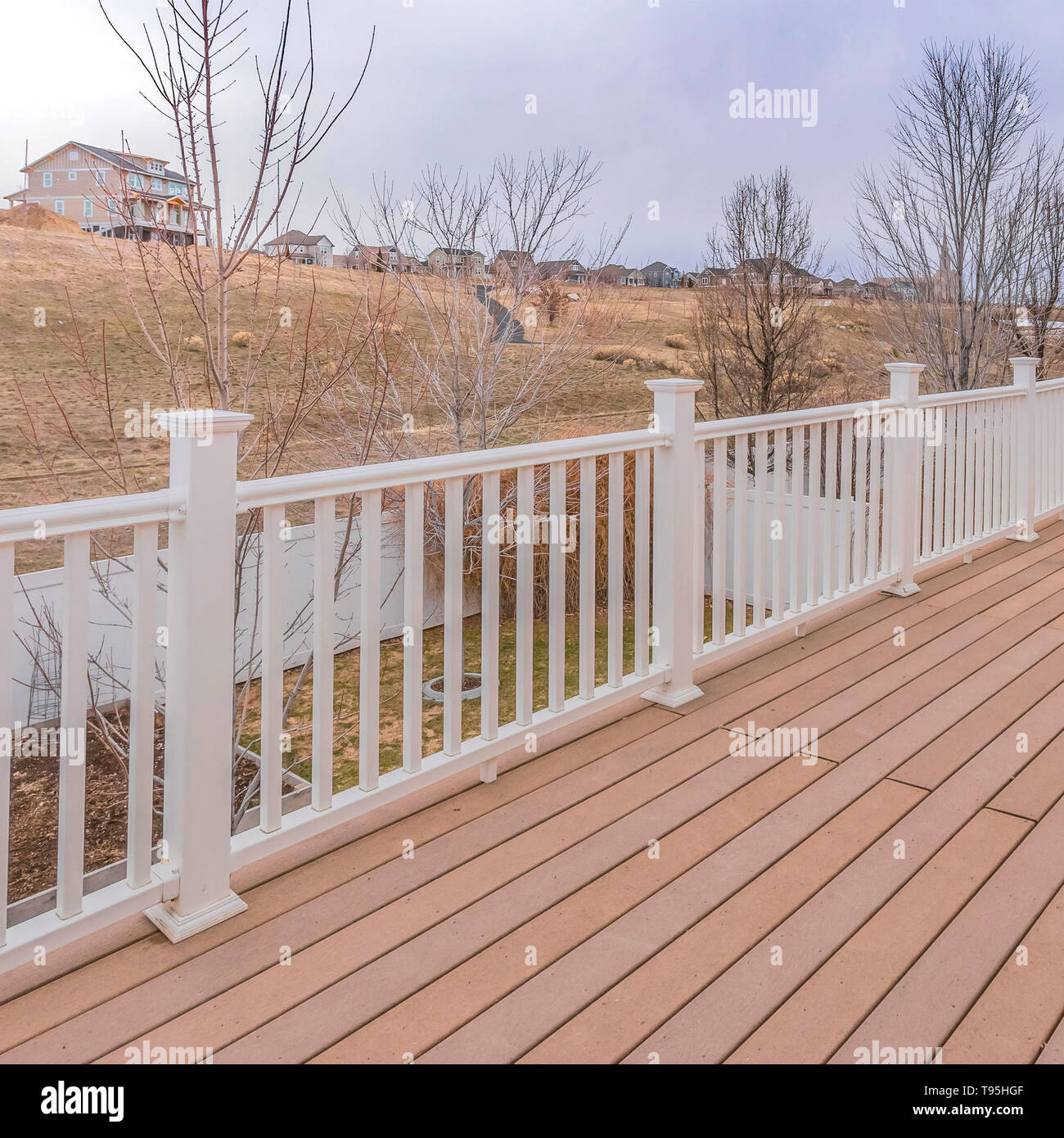 Square Spacious balcony of a home with wooden floor and white railing ...
