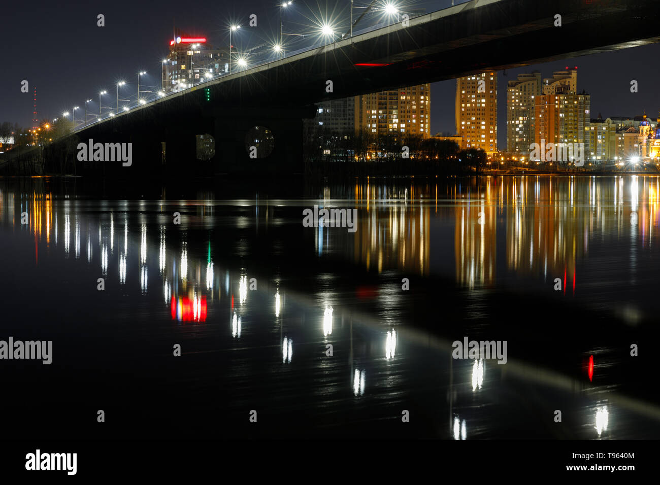 dark cityscape with illuminated bridge and reflection on river at night ...