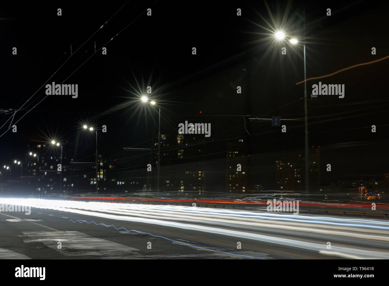 long exposure of lights on road at night near illuminated buildings ...