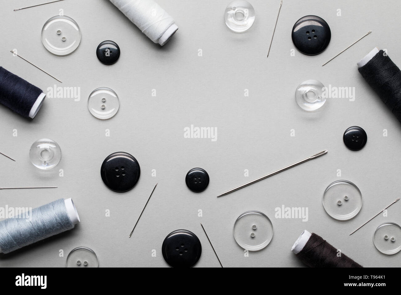 top view of black and transparent clothing buttons, needles and thread ...