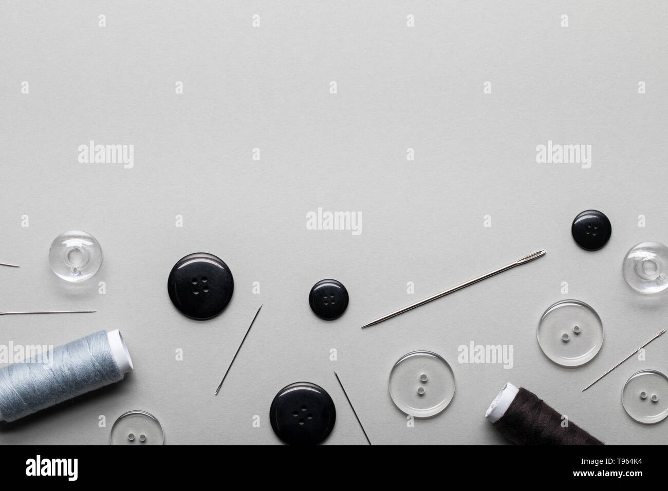 top view of clothing buttons, needles and thread coils isolated on grey ...