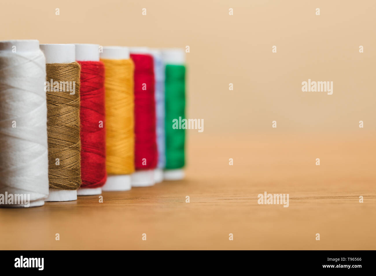 colorful cotton thread coils in row isolated on beige with copy space ...