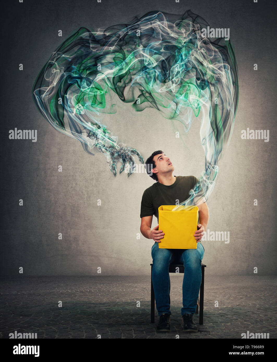 Scared man seated on a chair holding mystery box on knees looking up ...