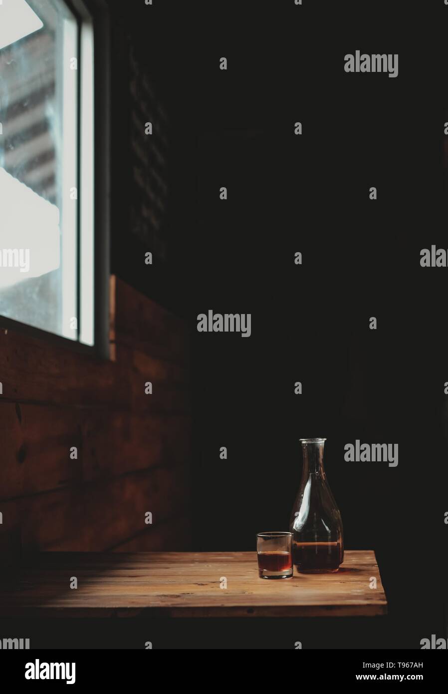 Bottle of alcoholic baverage under window Stock Photo - Alamy