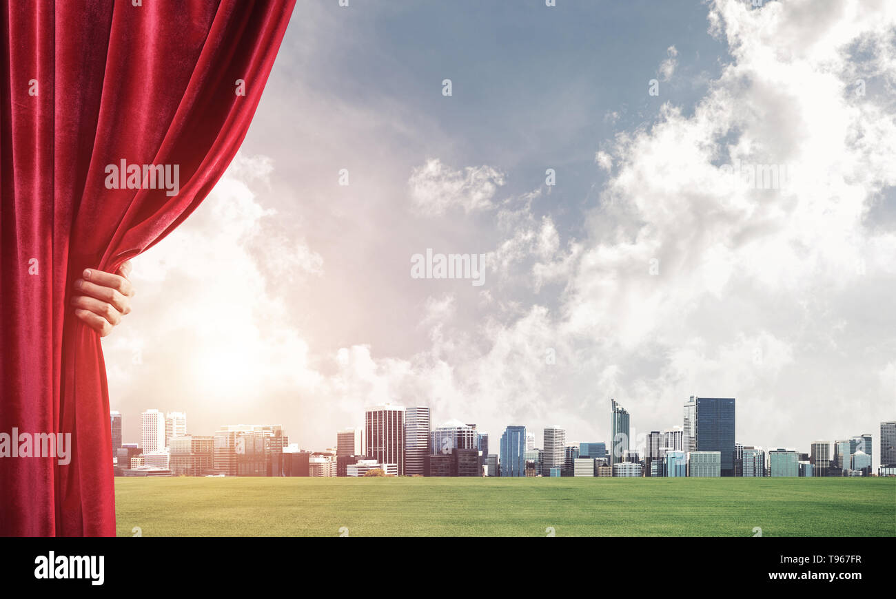 Green meadow behind red curtain and hand holding it Stock Photo - Alamy