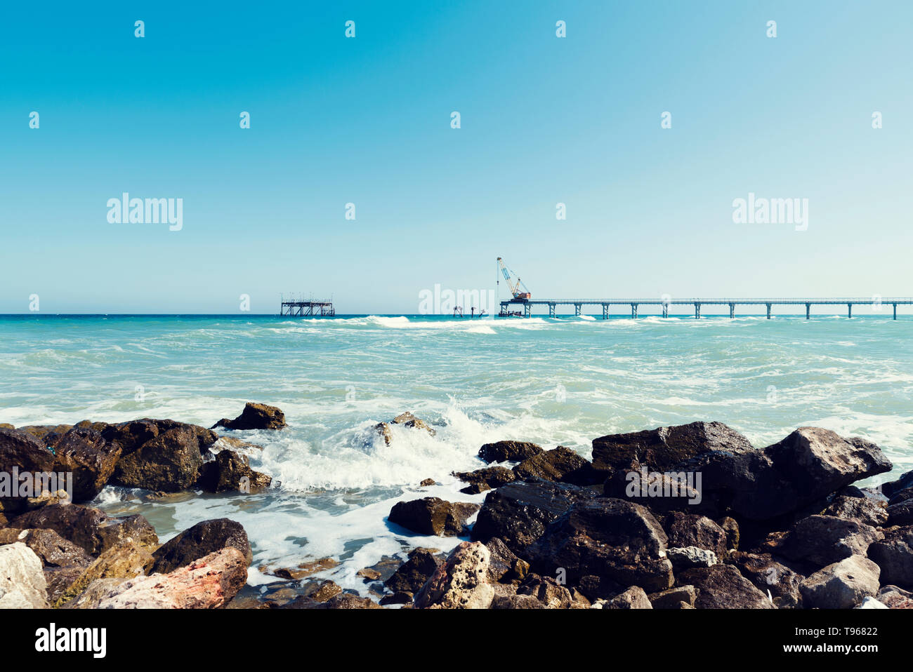 Sea landscape midday with rocks waves and constructions of the new pier ...
