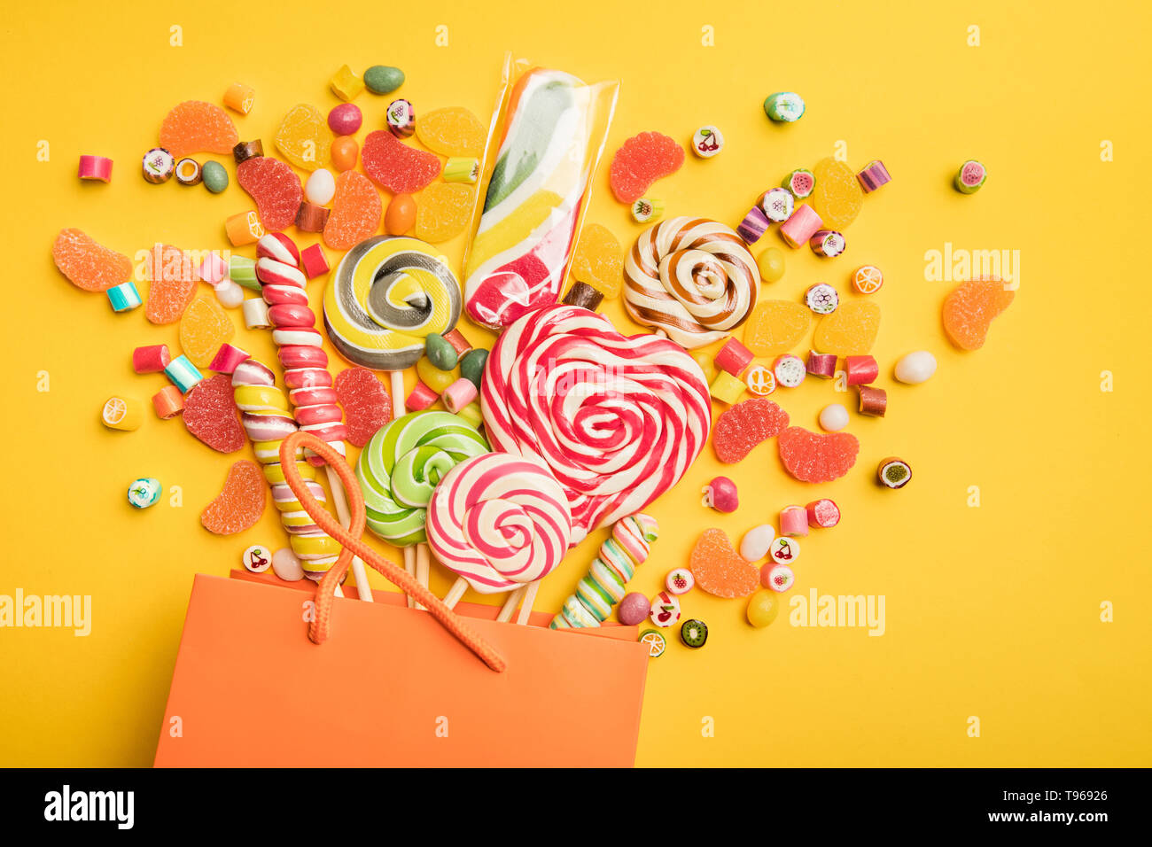 top view of tasty multicolored sweets scattered from paper bag on ...
