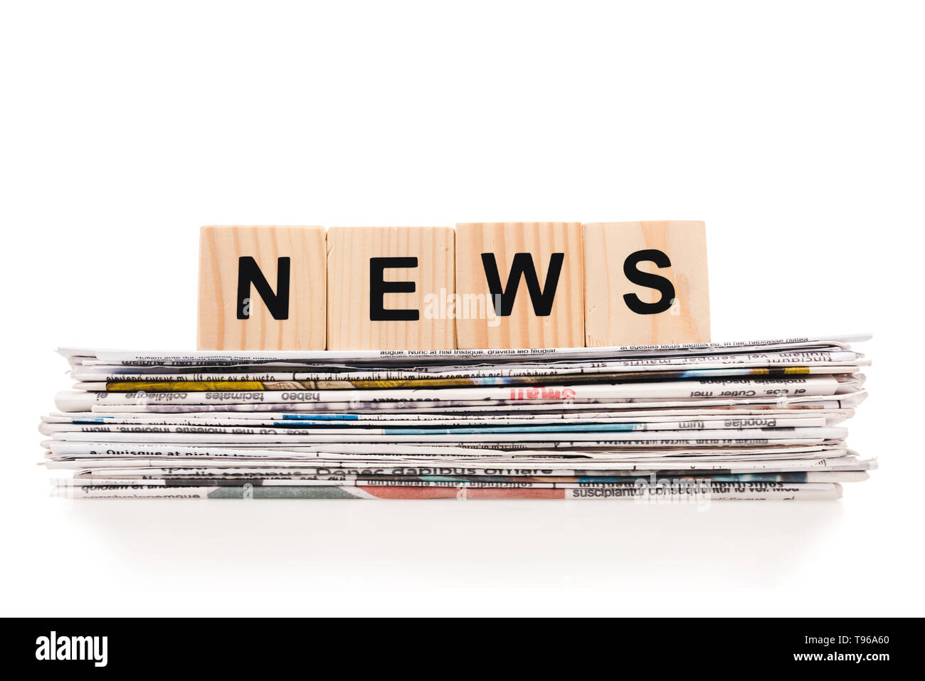 wooden blocks with news lettering on pile of print newspapers isolated ...
