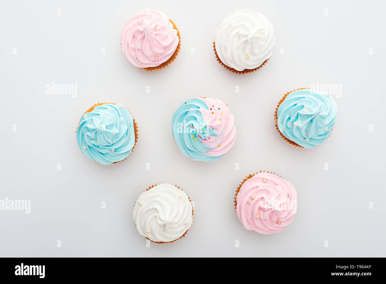 top view of delicious white, pink and blue cupcakes with sprinkles ...