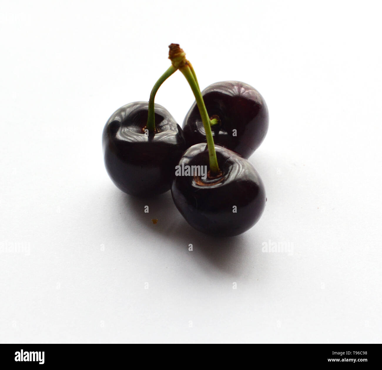 Three cherries joined together on a white background Stock Photo - Alamy