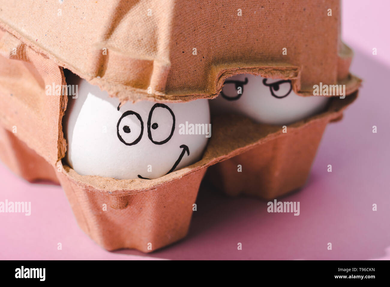 close up of eggs with angry and smiling face expressions in egg carton ...