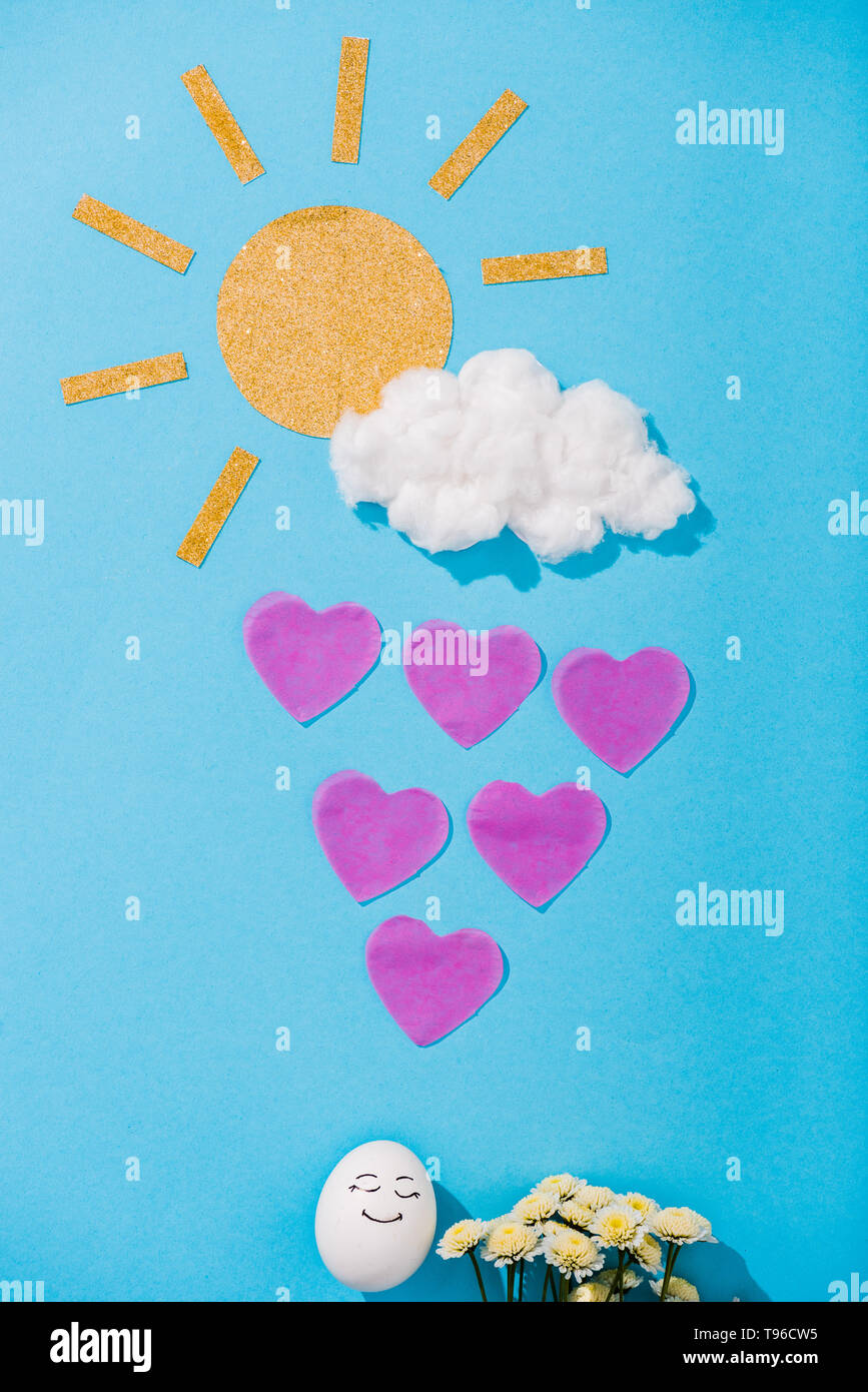 top view of paper sun, cotton candy cloud, egg with happy face ...
