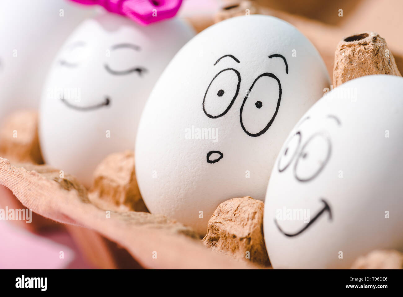 close up view of eggs with different face expressions in egg carton ...