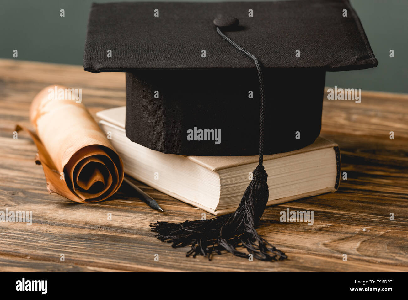 book, academic cap and scroll on wooden surface isolated on grey Stock ...