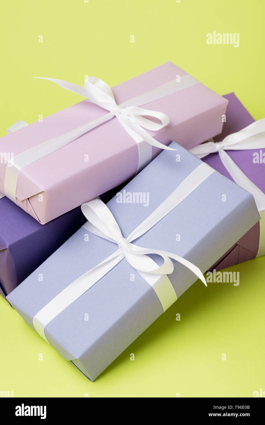 purple gift boxes with white ribbons on yellow surface Stock Photo - Alamy