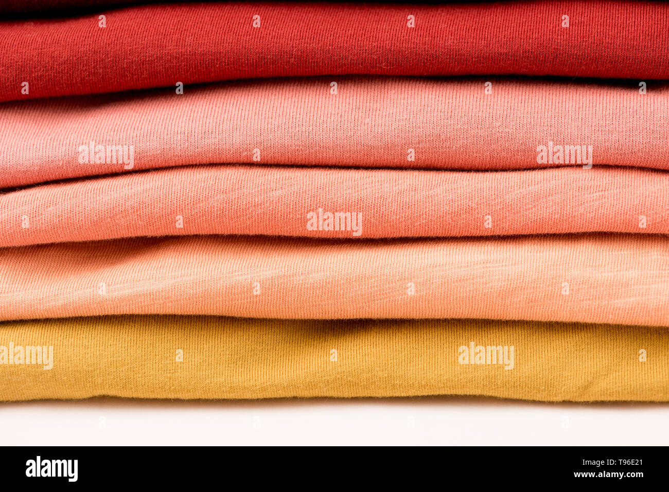 stack of folded colorful clothes on white surface Stock Photo - Alamy