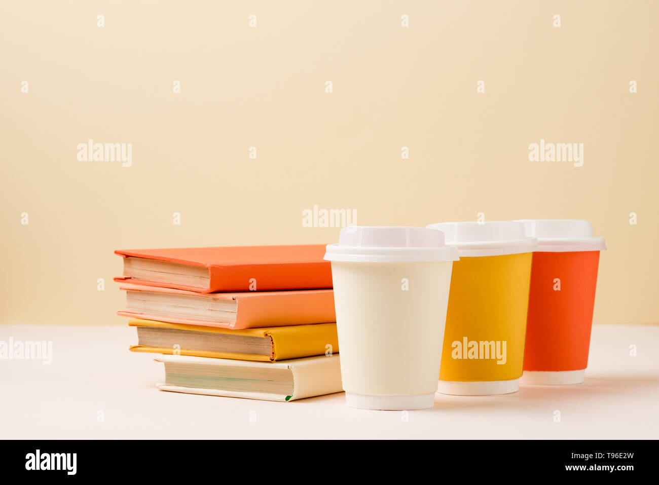 stack of books and colorful disposable cups on white surface isolated ...