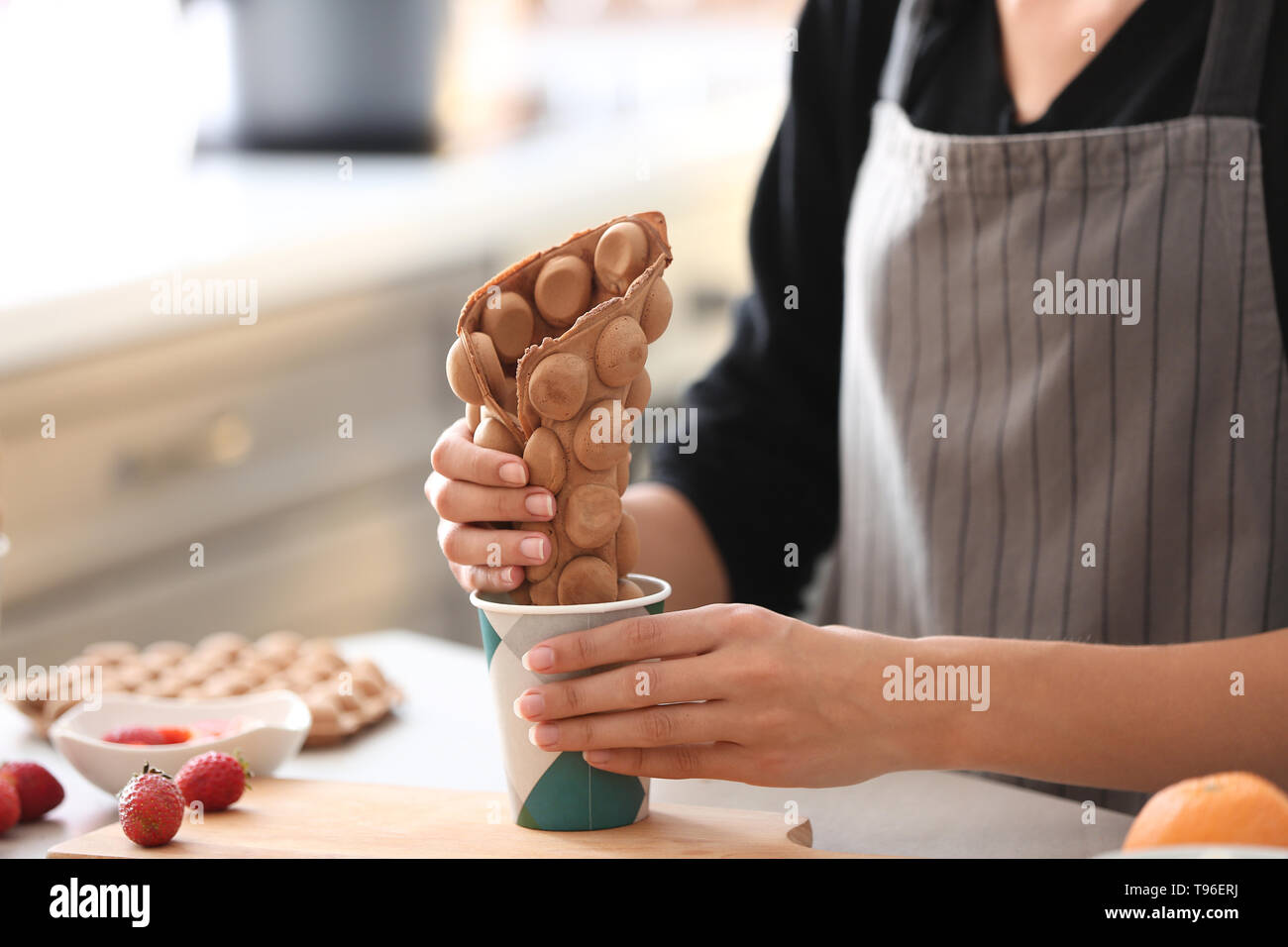 Woman preparing sweet bubble waffles in kitchen Stock Photo - Alamy