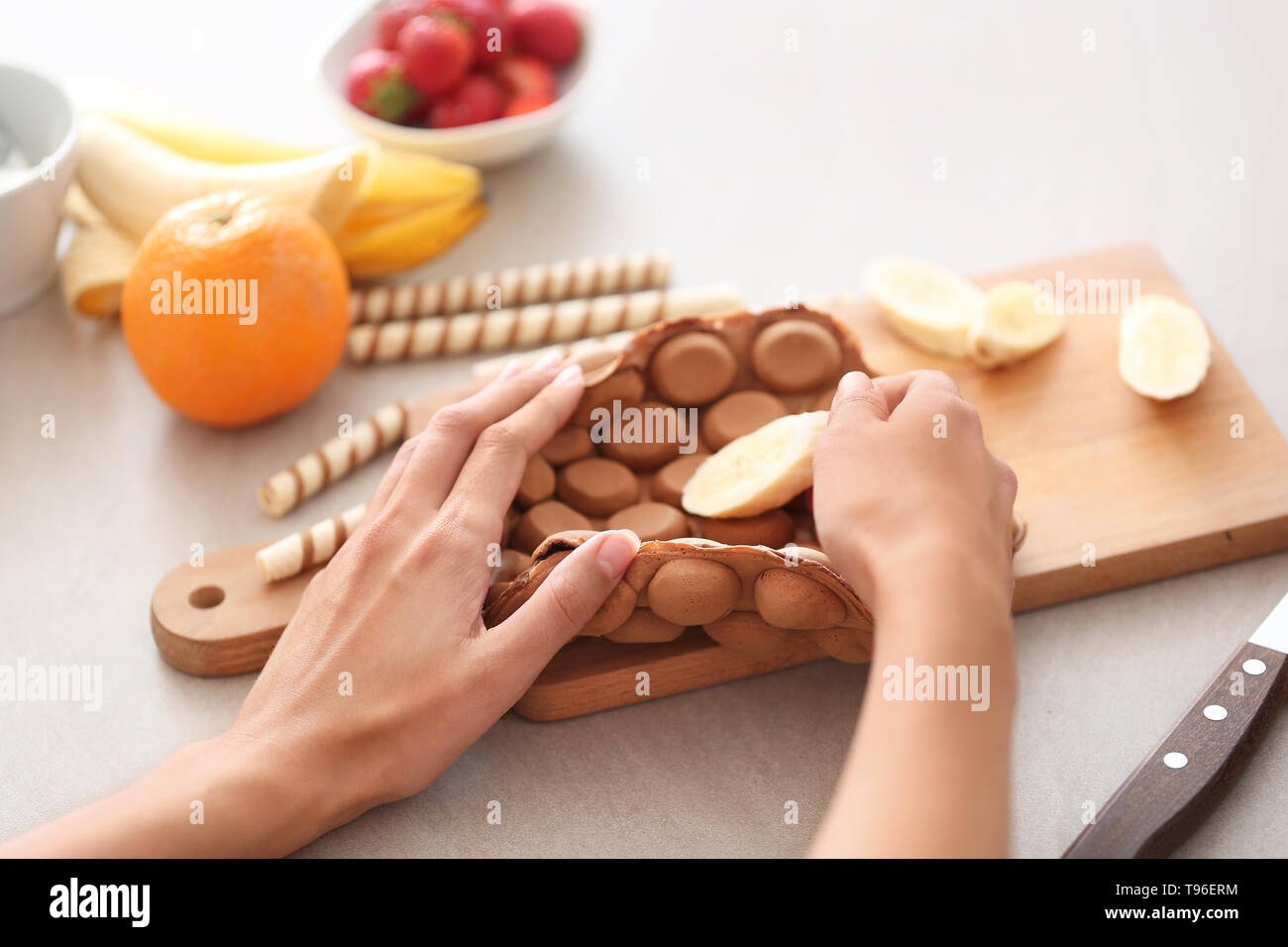 Woman preparing sweet bubble waffles at table Stock Photo - Alamy