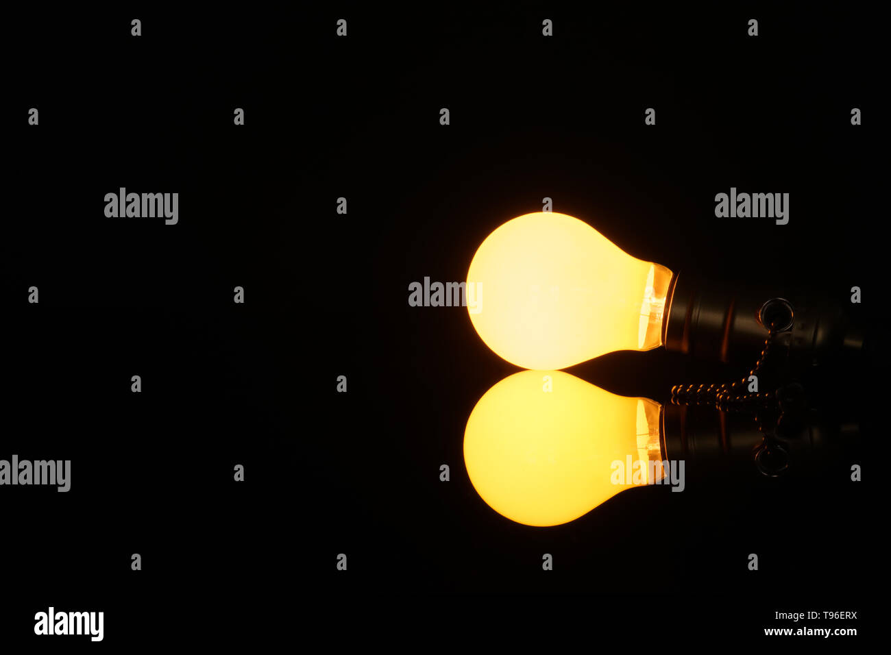 Glowing light bulb with reflection on black background Stock Photo - Alamy