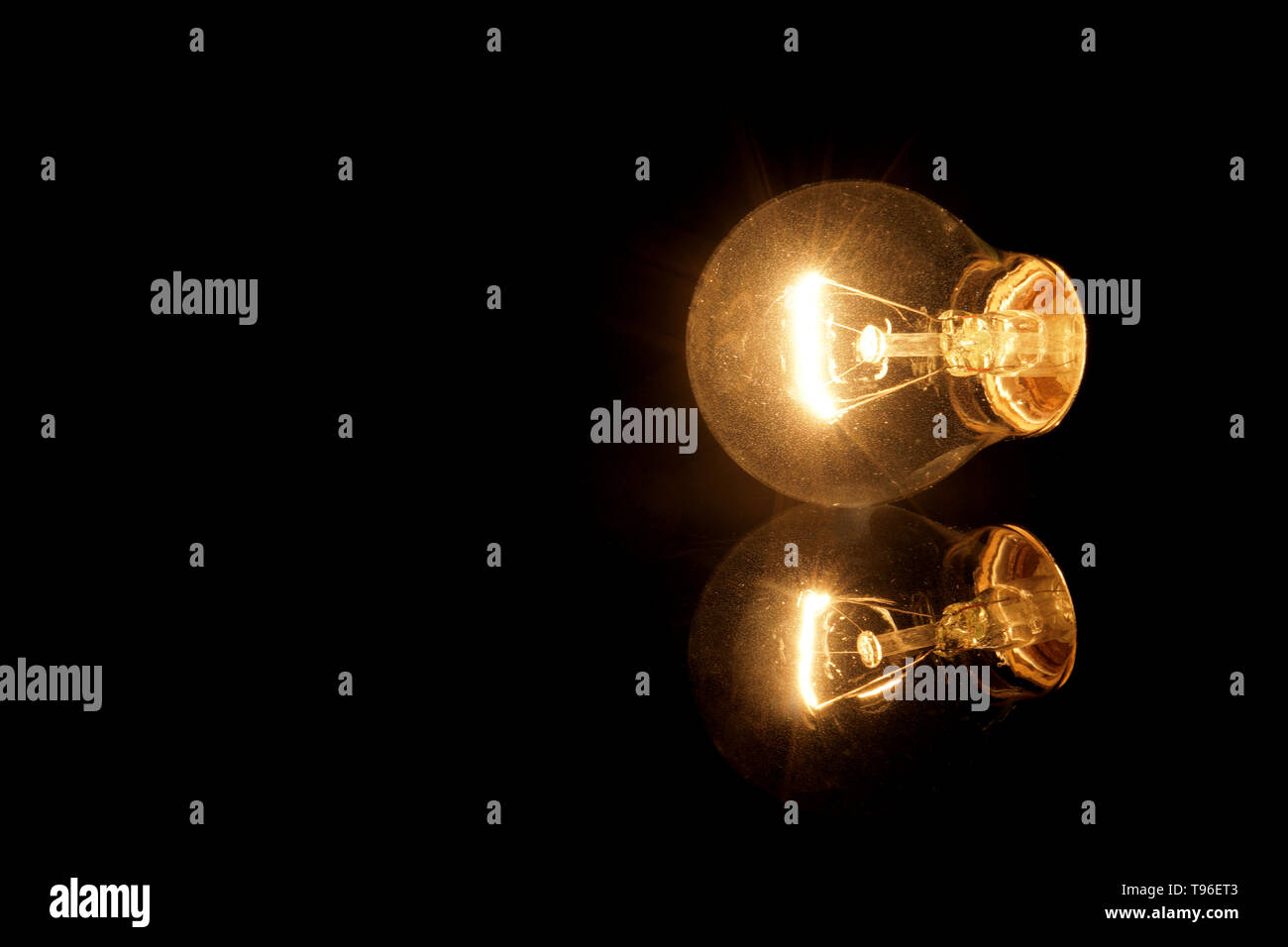 Glowing retro light bulb with reflection on black background Stock ...