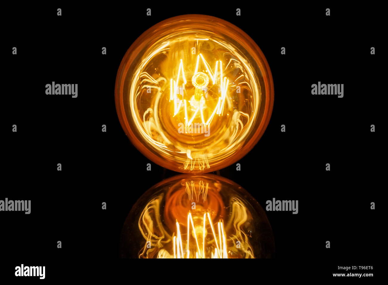 Glowing lamp bulb with reflection on black background Stock Photo - Alamy