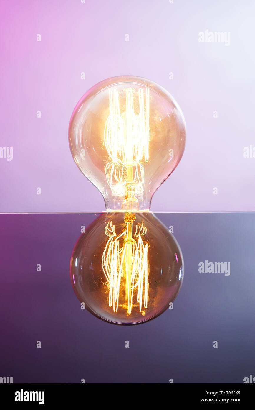Glowing retro light bulb with reflection on color background Stock ...