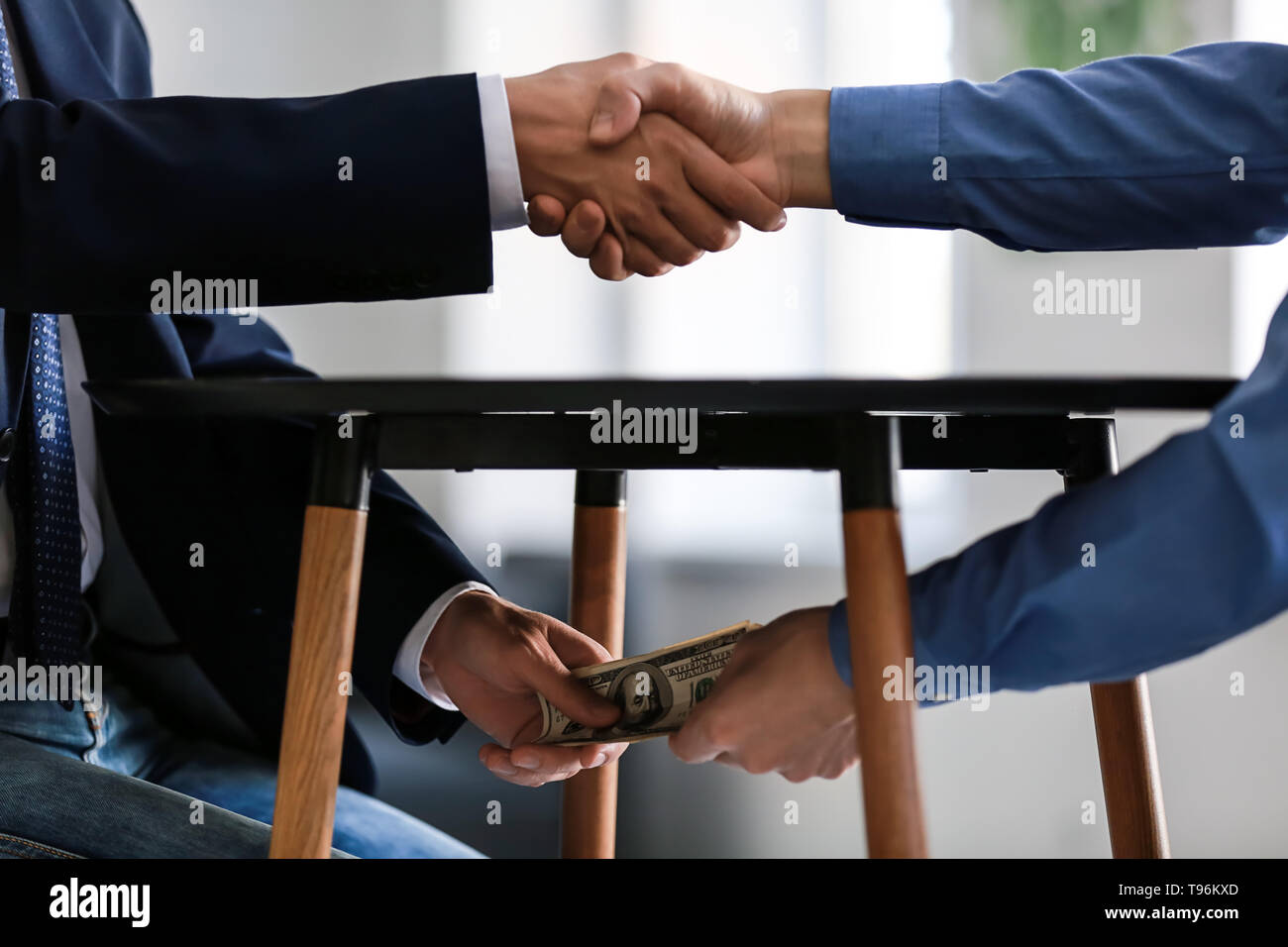 Businessman taking bribe from man under table. Corruption concept Stock ...