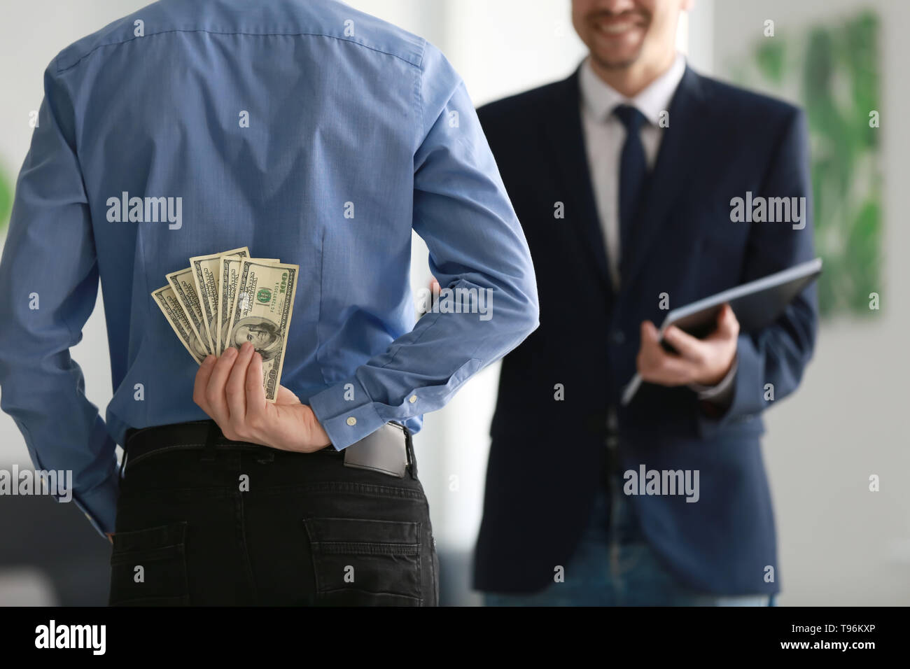 Man holding bribe for businessman behind back. Corruption concept Stock ...