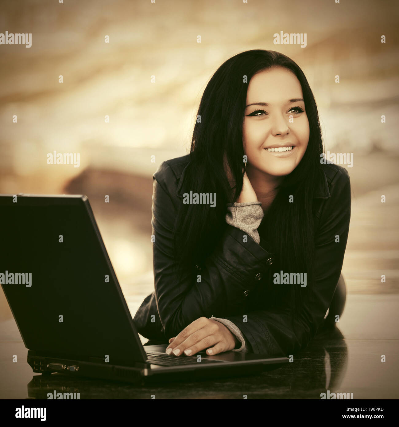 Happy young woman using laptop lying on parapet Stylish fashion model ...