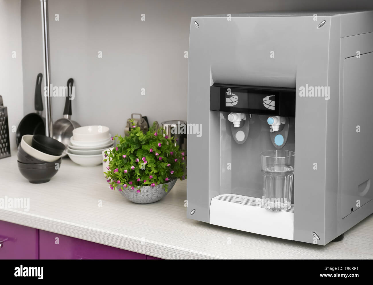 Modern water cooler with glass on kitchen table Stock Photo - Alamy