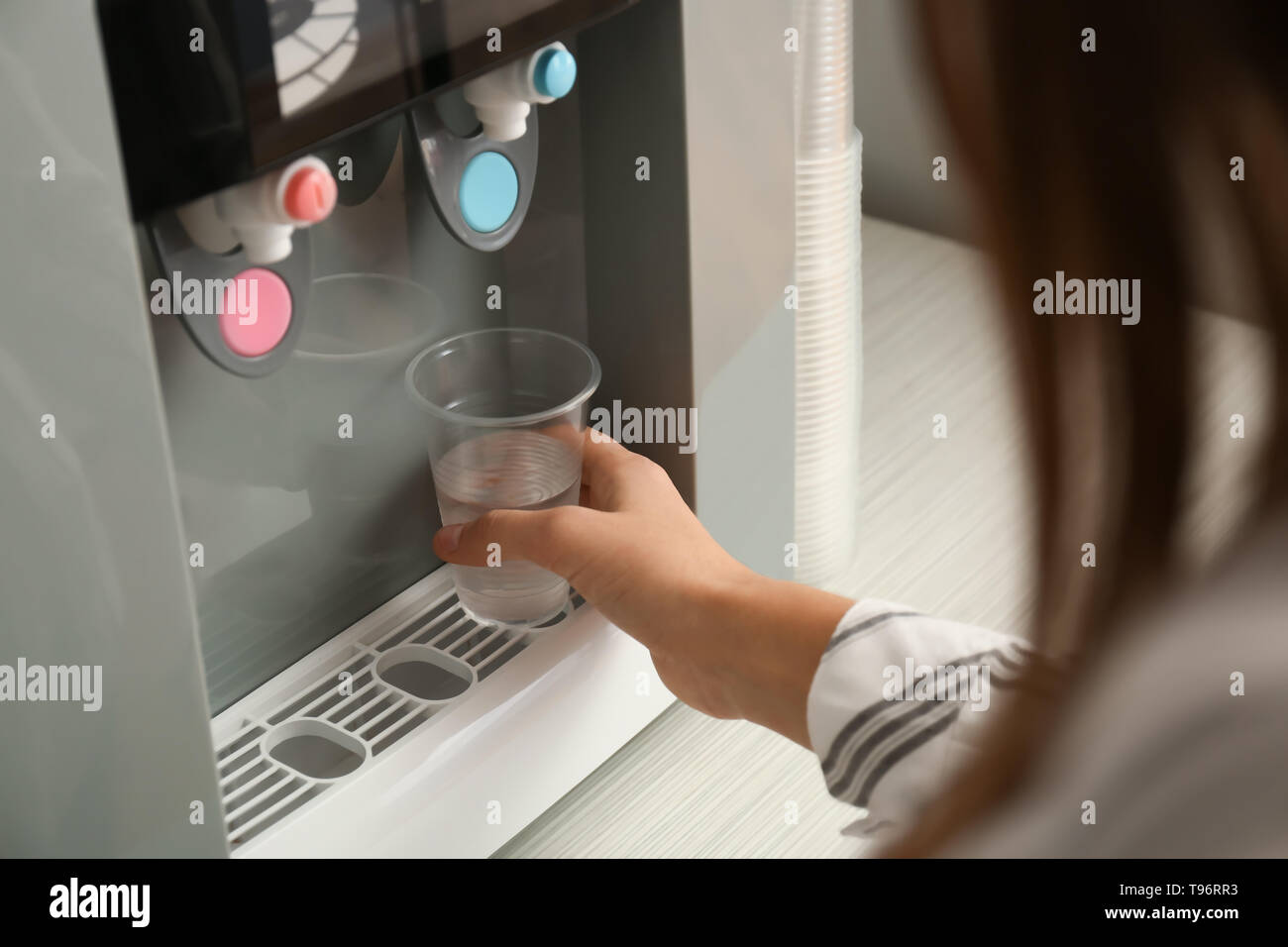 Woman filling plastic cup with water from cooler, closeup Stock Photo ...