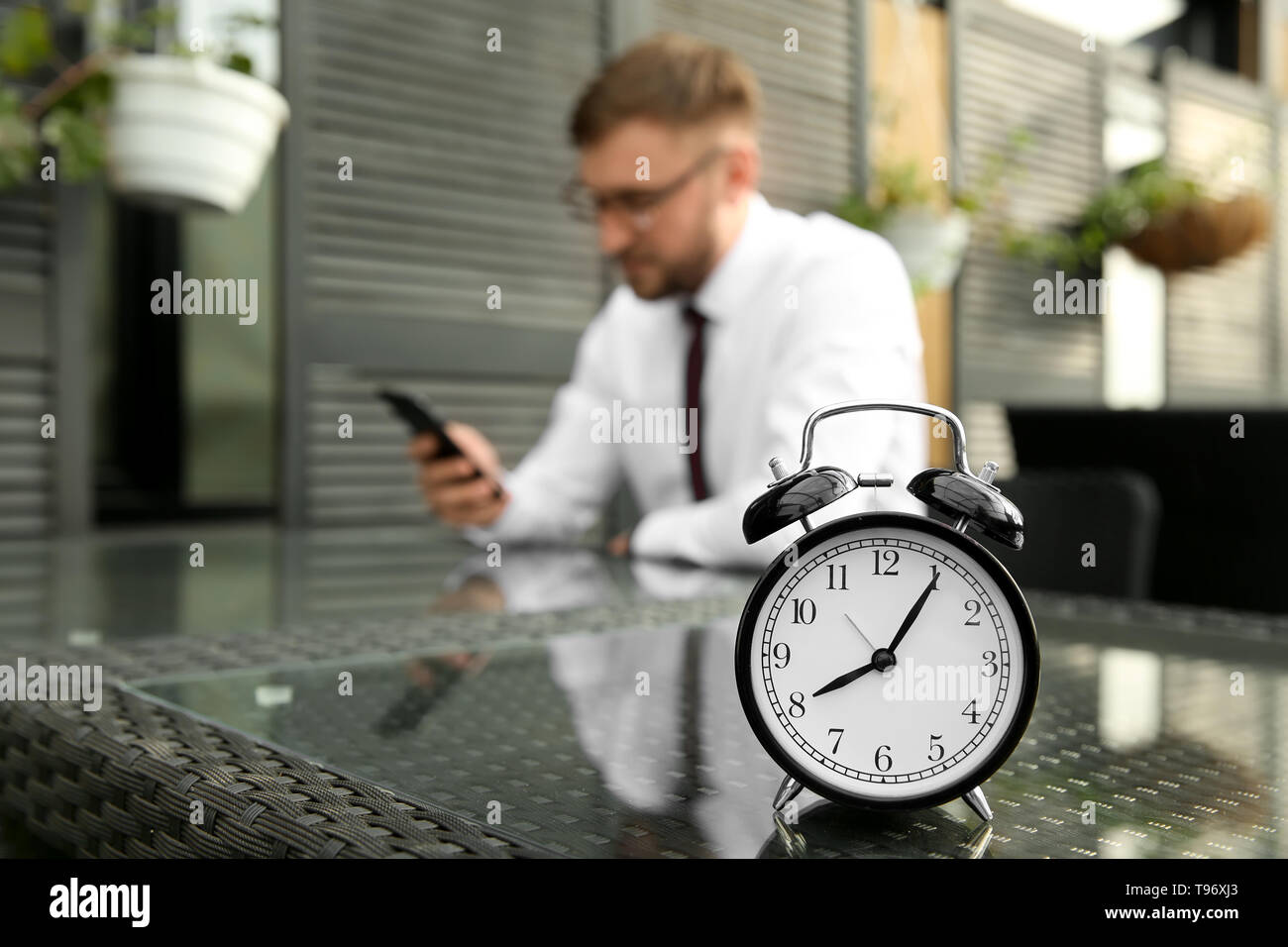 Alarm clock on table of businessman resting in cafe Stock Photo - Alamy