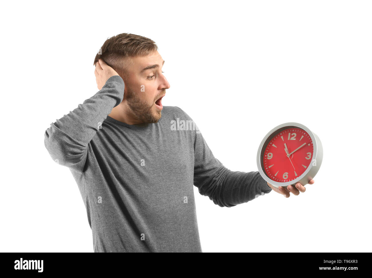 Emotional young man with clock on white background Stock Photo - Alamy
