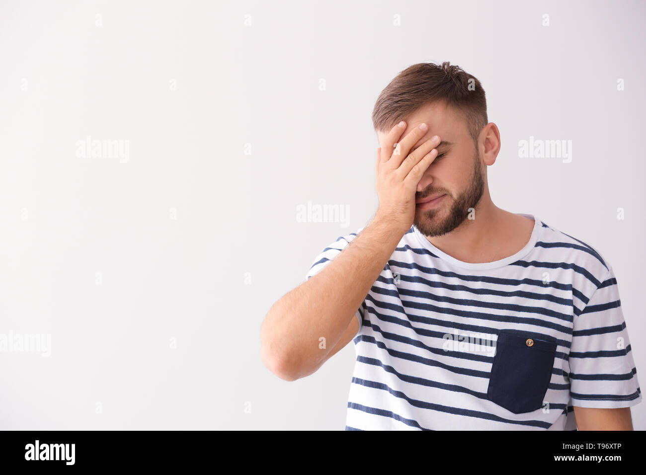 Emotional young man after making mistake on white background Stock ...