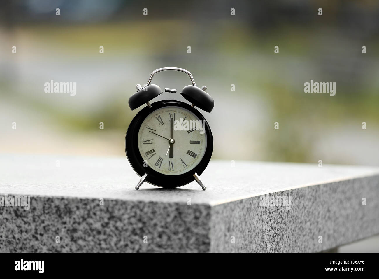 Alarm clock with Rome numbers on blurred background outdoors Stock ...