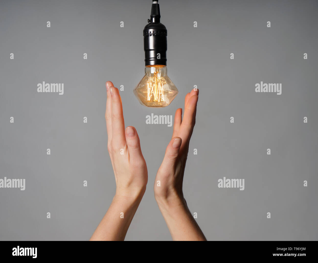 Female hands with glowing light bulb on grey background Stock Photo - Alamy
